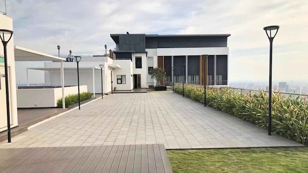 Um edifício moderno com telhado plano, calçada pavimentada e área gramada.