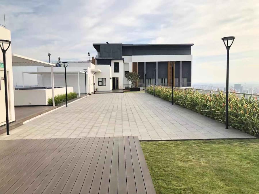 Um edifício moderno com telhado plano, calçada pavimentada e área gramada.