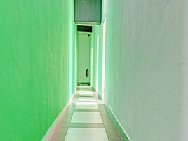 Um corredor estreito com paredes verdes e chão de azulejos.