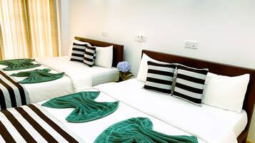 Quarto de hotel com duas camas, cada uma com colcha listrada e almofadas, e uma toalha verde na cama.