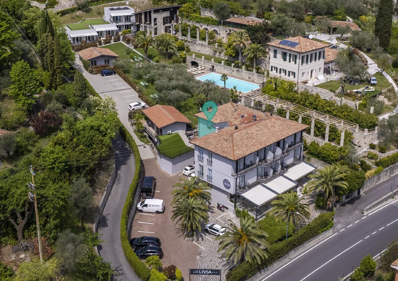 Vista aérea de um bairro residencial com uma casa grande, piscina, jardim e área de estacionamento.