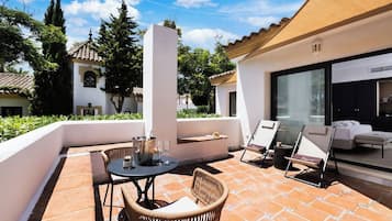 Pátio com mesa e cadeiras, um espaço de estar pequeno e vista para um edifício com grandes janelas.