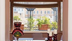 Janela com vista para edifícios e plantas em vasos.