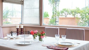 Mesa de jantar posta com pratos, copos e velas, com vista para o verde lá fora.