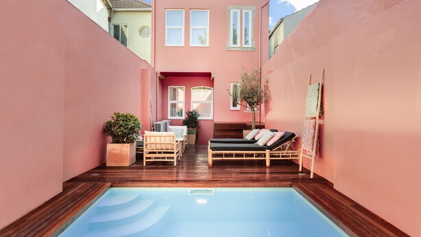 Uma área de piscina moderna com deck de madeira, uma espreguiçadeira e uma mesinha.