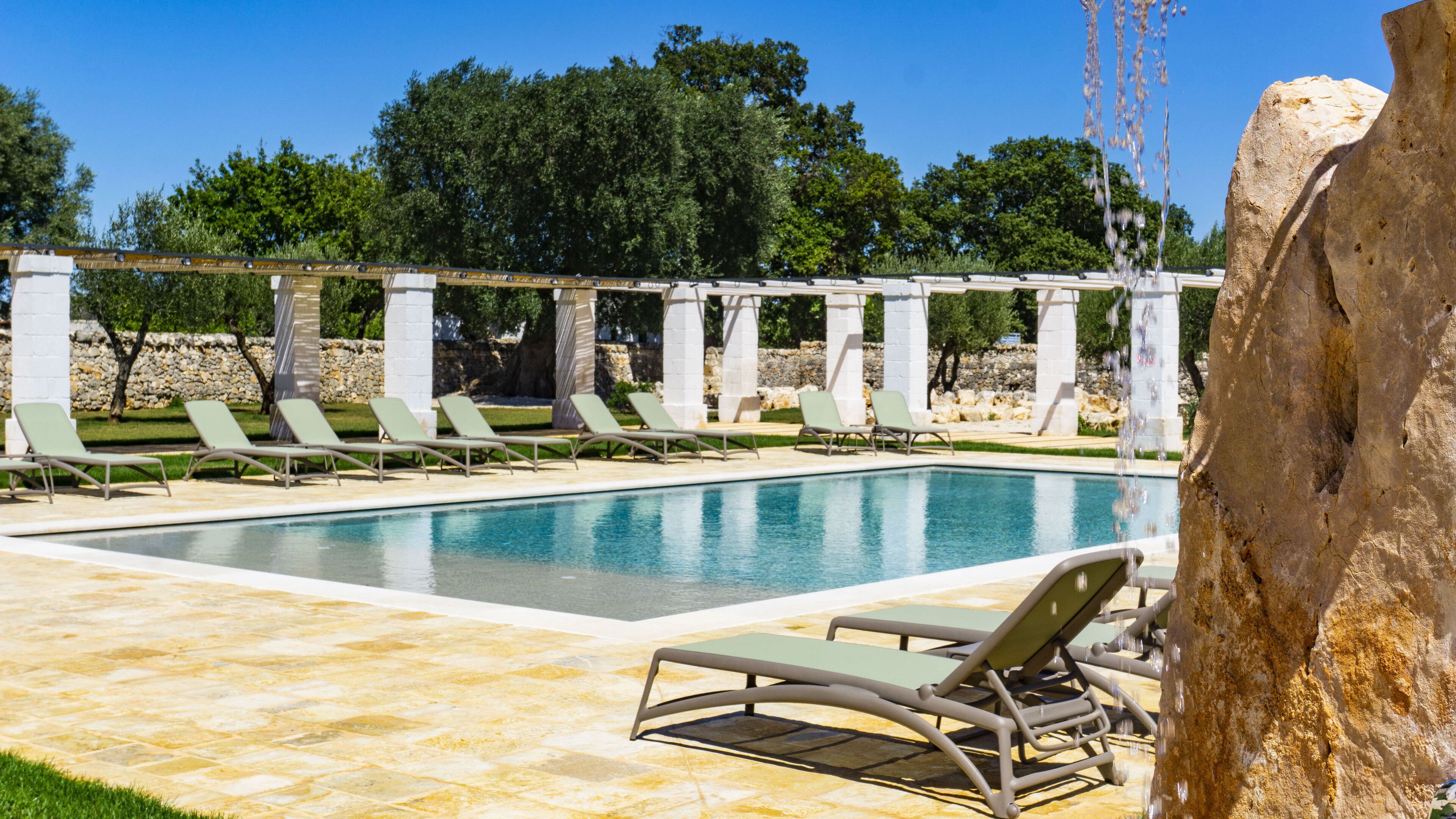 Uma piscina com espreguiçadeiras e uma estrutura de pérgola.