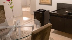 Uma cozinha moderna com uma mesa de jantar de vidro, uma geladeira e um balcão.