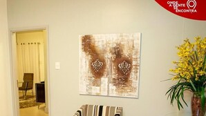 Uma sala de estar moderna com uma poltrona listrada, um objeto decorativo na parede e um vaso com flores amarelas.