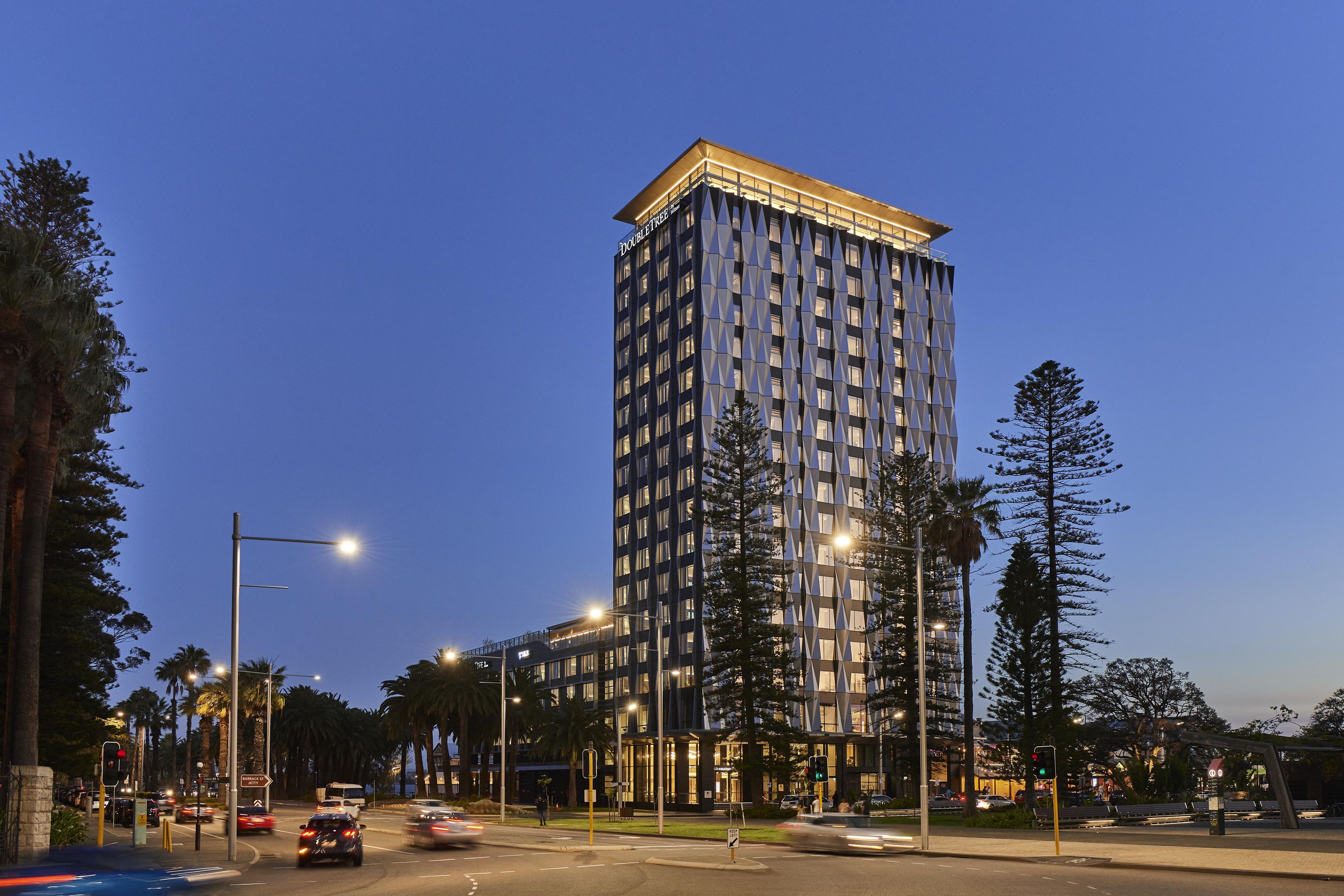 Um edifício alto com design arquitetônico moderno, com entrada destacada e vários andares.