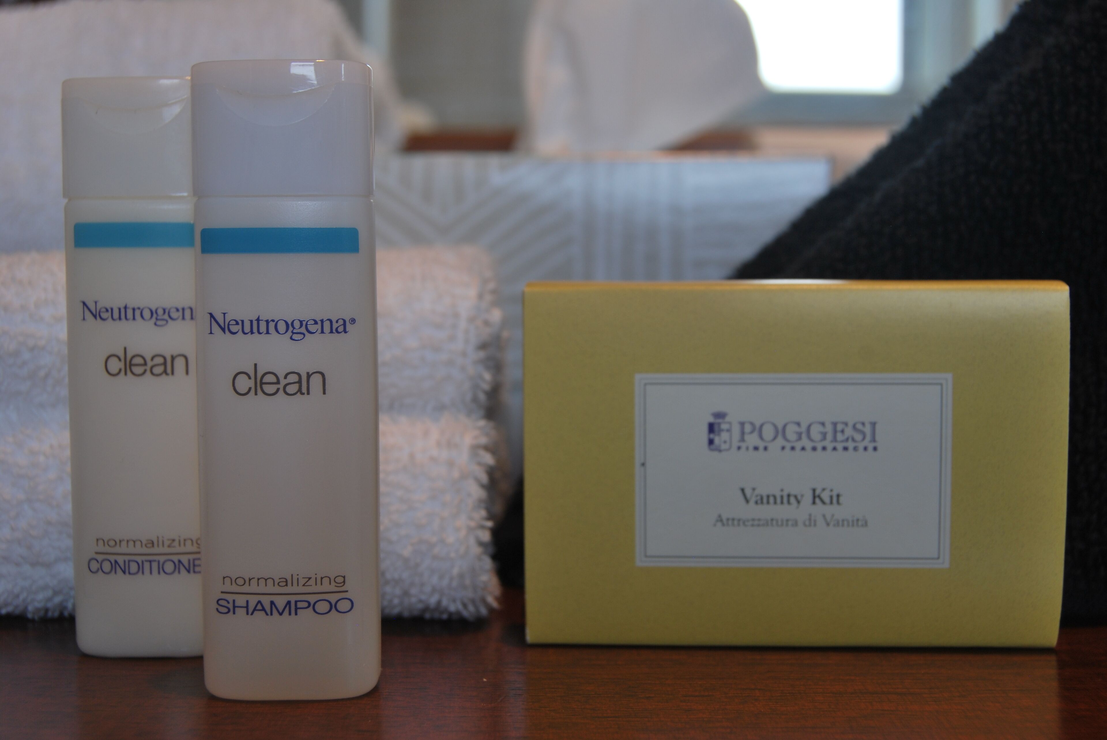 Duas embalagens de shampoo purificante e normalizante Neutrogena e um kit de higiene Poggesi sobre uma superfície de madeira.