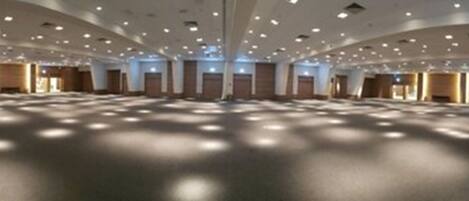Um amplo hall de hotel com teto alto e várias luzes embutidas.