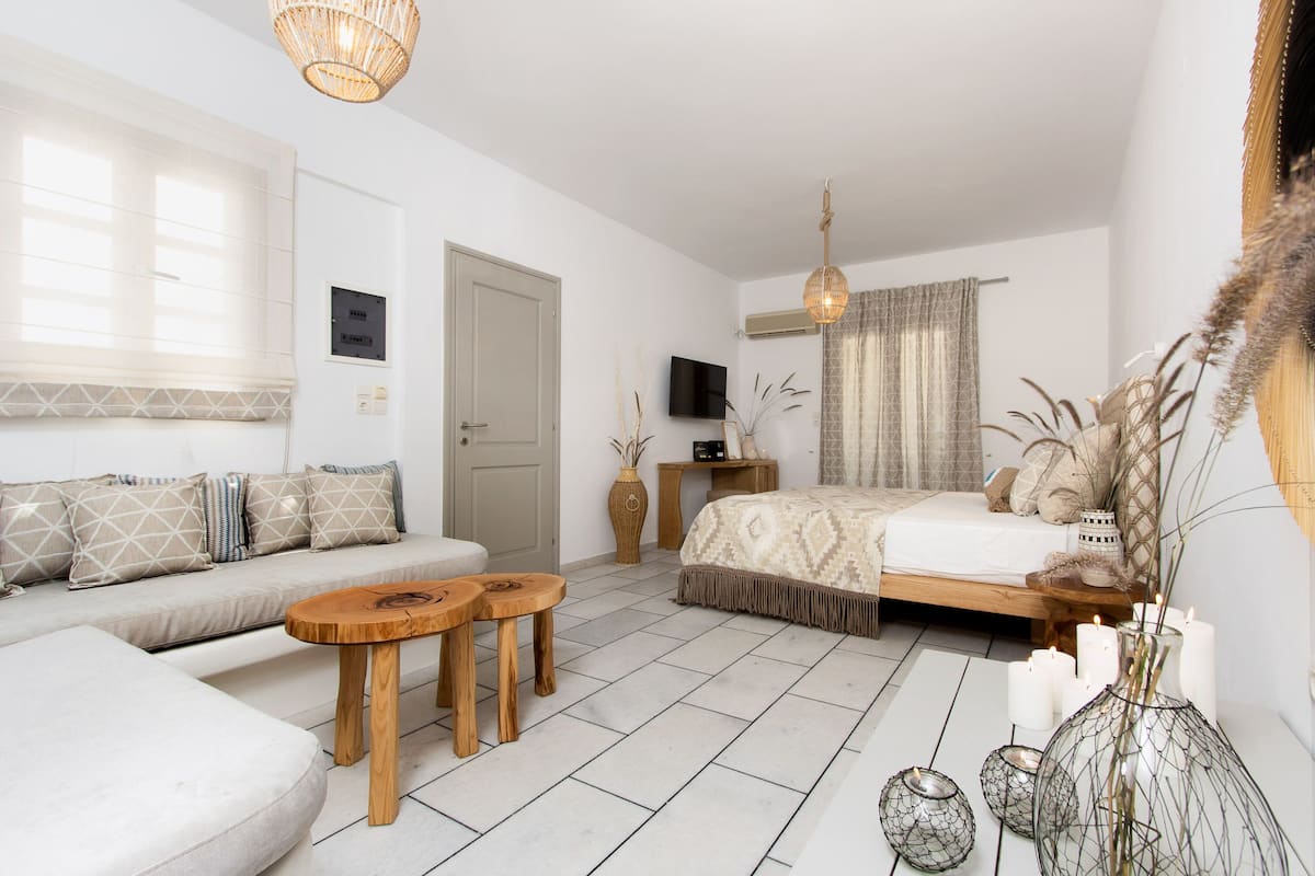 Quarto moderno com cama, sofá e uma pequena mesa de madeira.