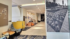 Um lobby de hotel moderno com balcão de recepção, área de estar e uma grande fotografia de uma mesquita fixada na parede.