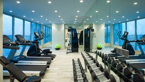 Uma academia com esteiras, halteres e bolas de exercício.
