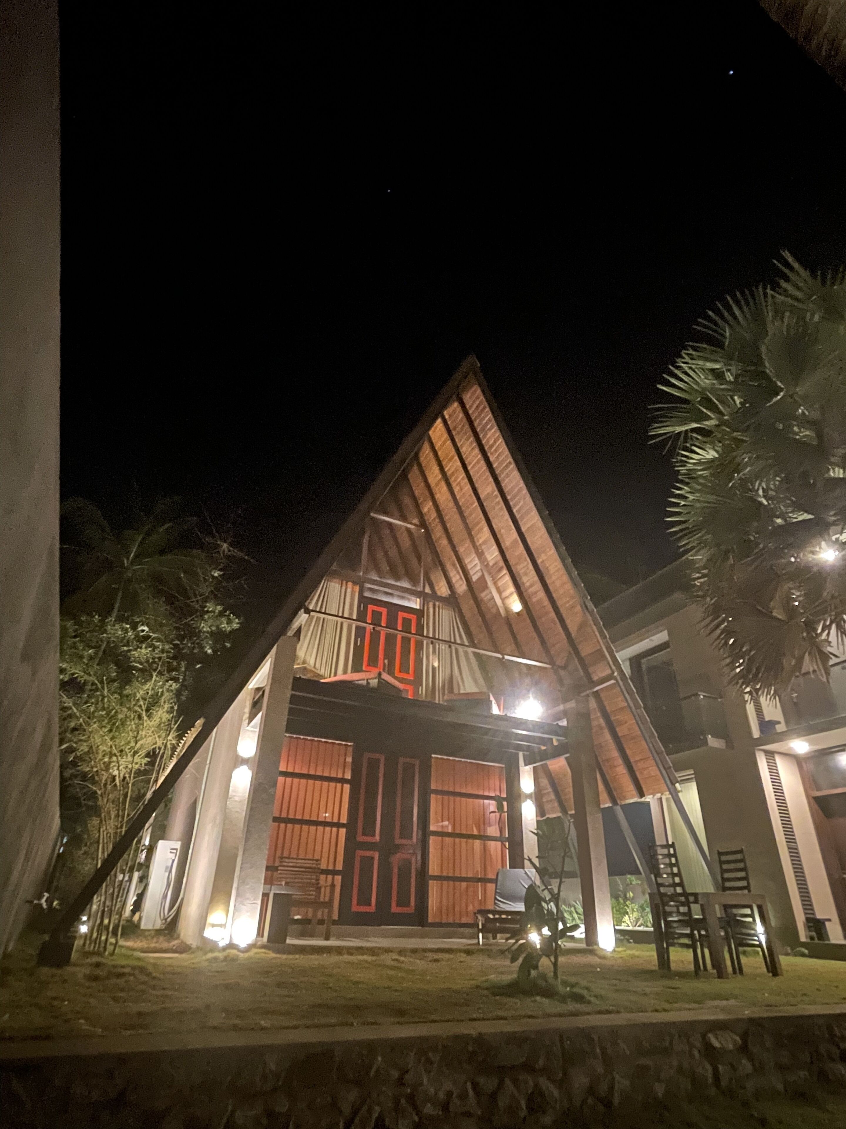 Um edifício moderno com telhado triangular, janelas amplas e uma varanda.