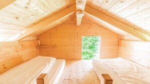 Uma cabana de madeira com duas camas e uma janela.