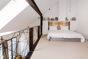 Quarto com cama, claraboia, escada e corrimão.