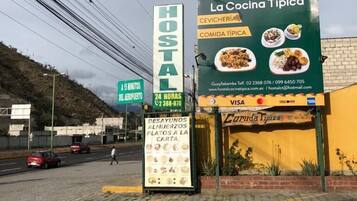 Placa de beira de estrada para um hotel chamado 'Hostal La Cocina Típica', com um menu e informações de contacto.