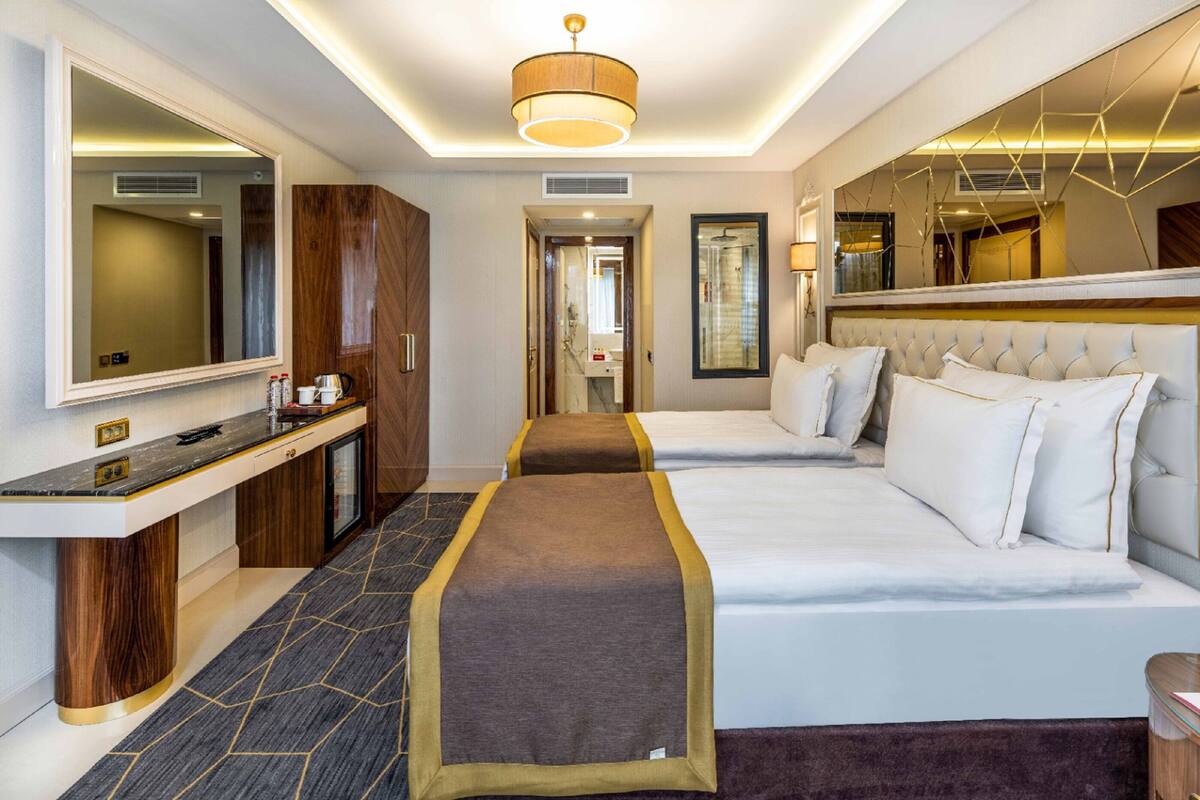 Quarto de hotel com uma cama grande, uma mesa de cabeceira, um espelho e vista para o corredor.