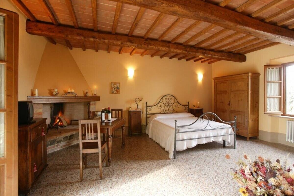 Quarto com lareira, uma cama, escrivaninha de madeira e guarda-roupa.