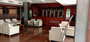 Um hall com sofás de couro branco, um balcão de recepção e um relógio.