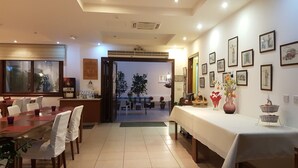 Uma sala de jantar ampla, com uma mesa comprida, cadeiras e um serviço de buffet.