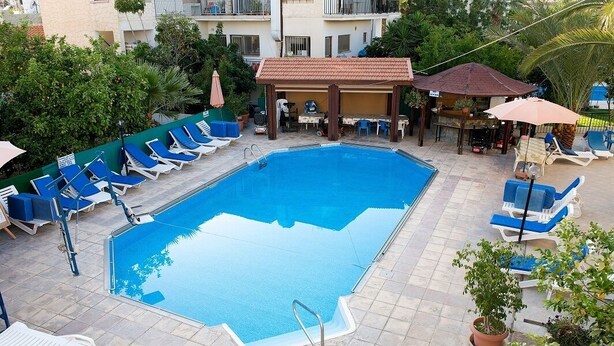Piscina retangular com água azul, rodeada por espreguiçadeiras e guarda-sóis.