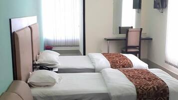 Quarto de hotel com duas camas, um sofá, uma escrivaninha e um ventilador de teto.