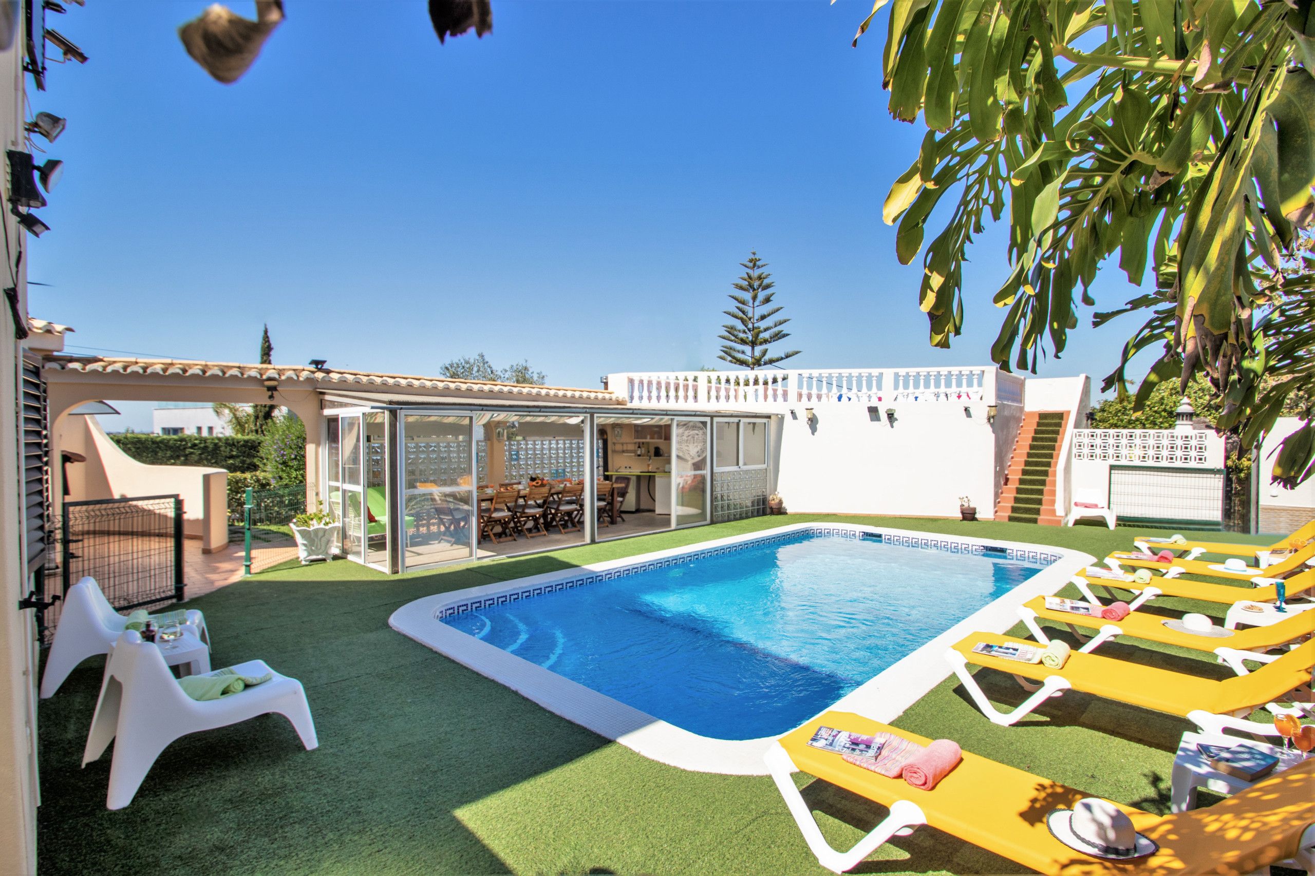 Piscina com espreguiçadeiras e área de estar coberta.