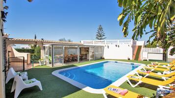 Piscina com espreguiçadeiras e área de estar coberta.