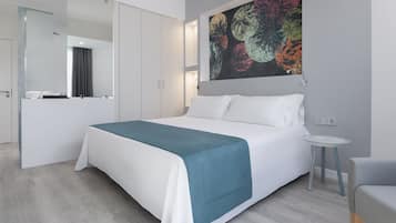 Quarto de hotel moderno com uma cama grande, uma mesinha de cabeceira, uma cadeira, um guarda-roupa e um quadro abstrato grande na parede.