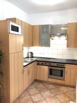 Uma cozinha compacta com armários de madeira, micro-ondas embutido, fogão e pia.
