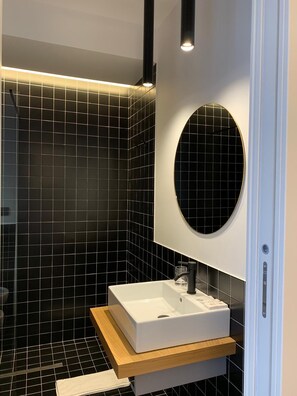 Quarto Quádruplo Deluxe, 1 cama king-size, junto ao pátio | Casa de banho | Um polibã, um chuveiro fixo, artigos de higiene pessoal grátis 
