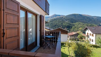 Varanda com mesa e cadeiras, vista para uma paisagem montanhosa.