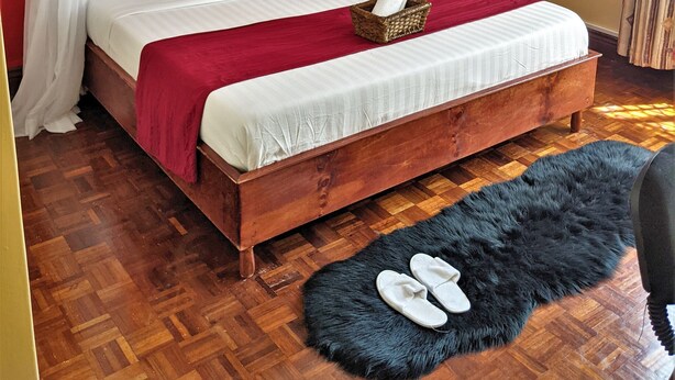 Quarto com cama de madeira, paredes vermelhas, roupa de cama branca e dossel.