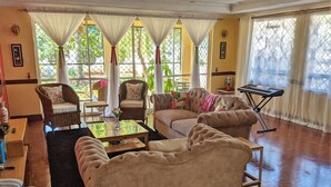 Uma sala de estar espaçosa com uma janela grande, um piano e assentos confortáveis.