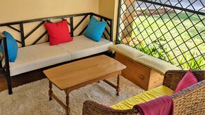 Uma área de estar acolhedora ao ar livre, com sofá, mesa de madeira e móveis de vime.