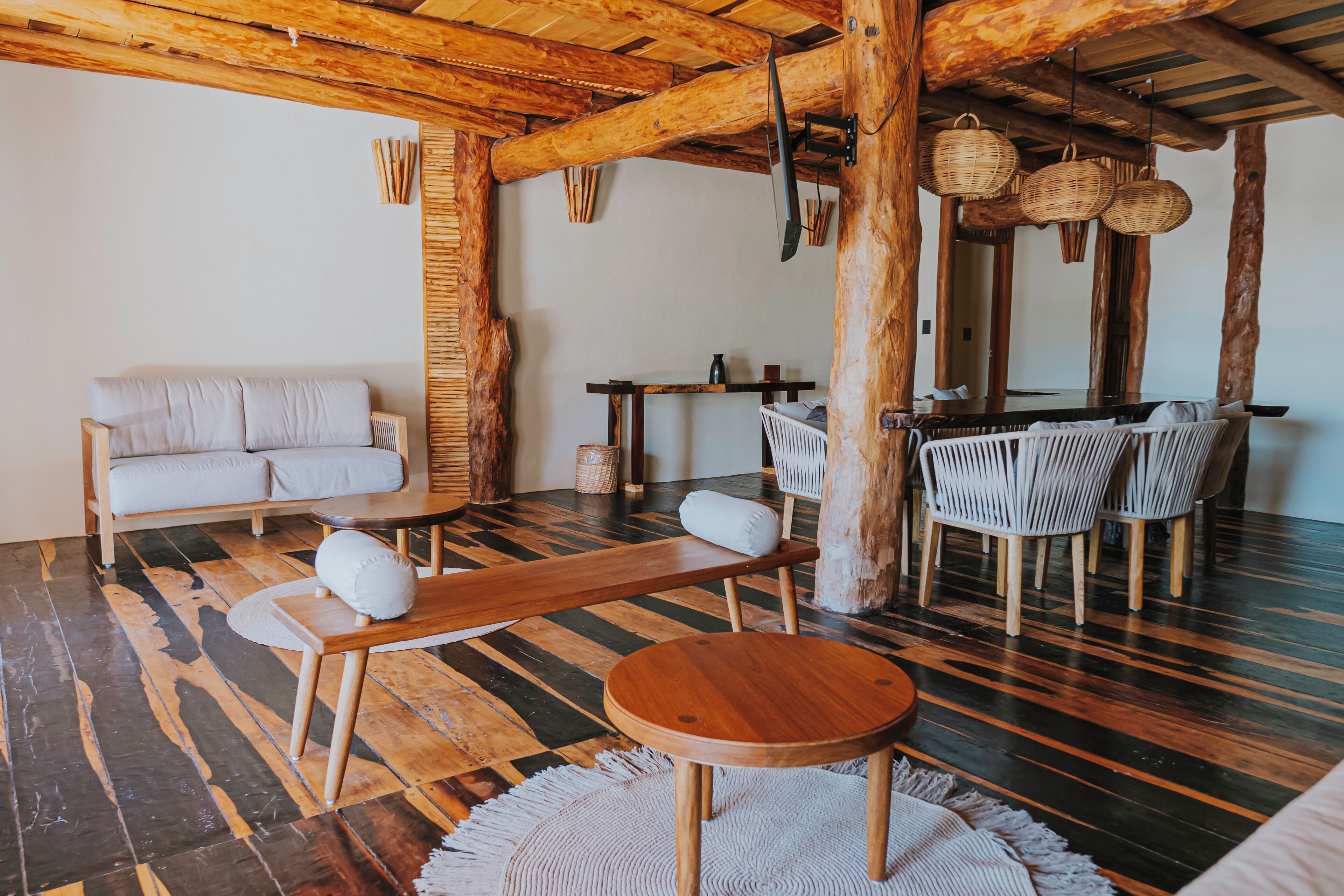 Um interior rústico com um banco de madeira, uma mesa redonda e um sofá.