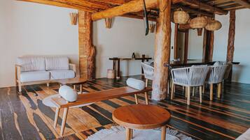 Um interior rústico com um banco de madeira, uma mesa redonda e um sofá.