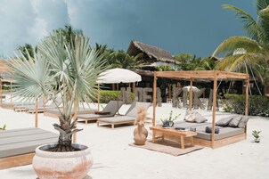 Praia particular, areia branca, espreguiçadeiras, guarda-sóis
