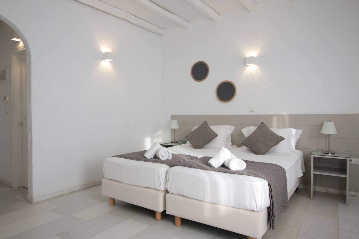 Quarto com uma cama de casal, duas mesas de cabeceira e iluminação na parede.