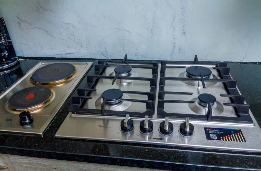 Uma cozinha com fogão a gás Bosch, cafeteira e micro-ondas.