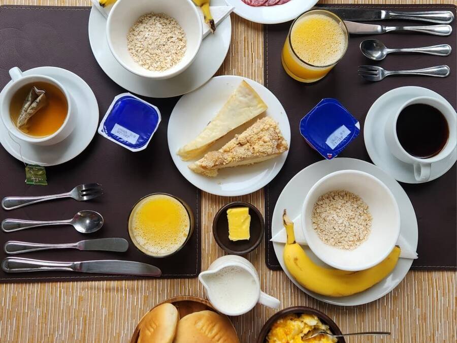 Mesa posta para o café da manhã, com diversos alimentos e utensílios.