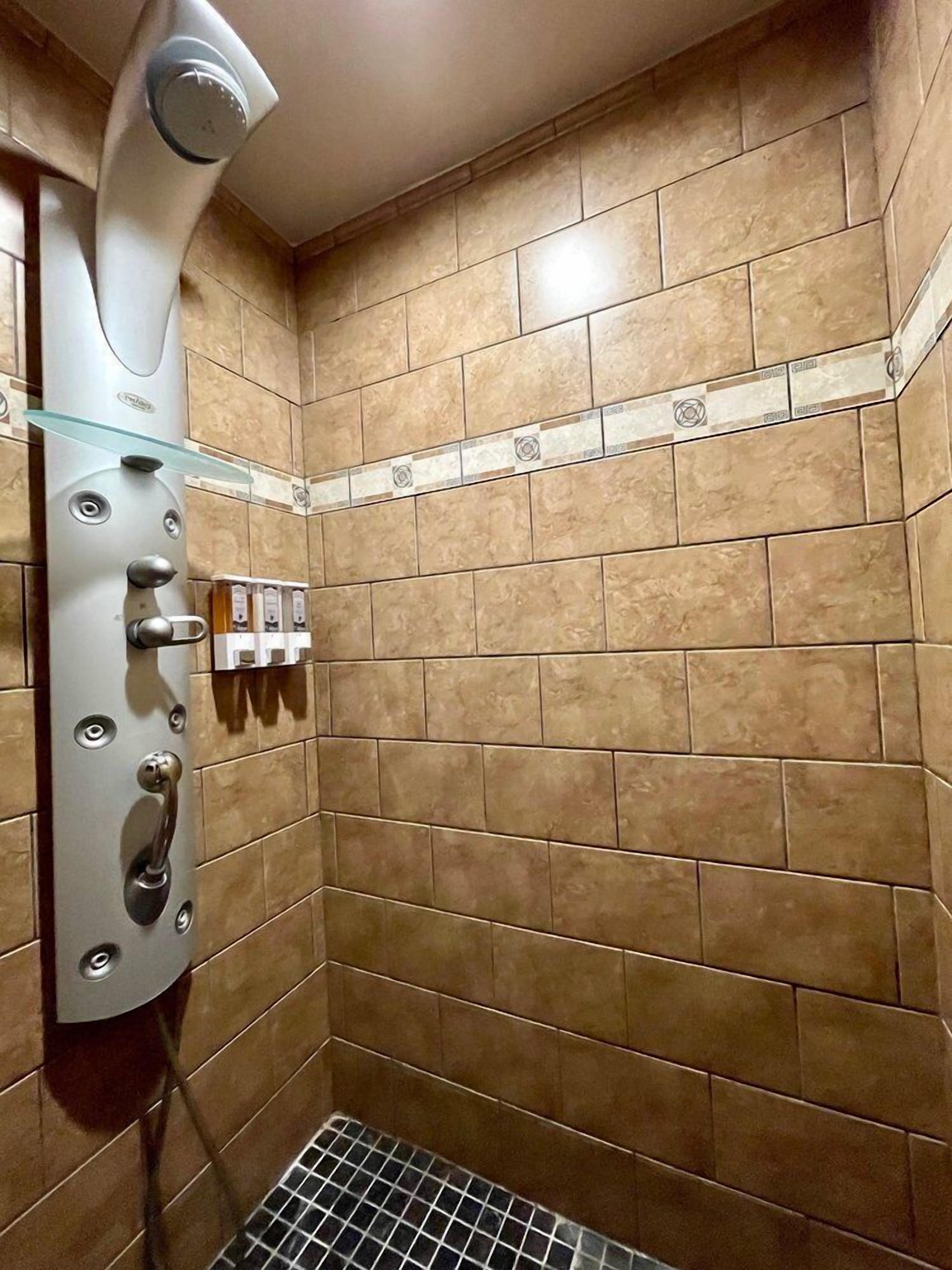 Chuveiro com design moderno, apresentando painel de vidro e painel de controle com vários botões e uma alça.