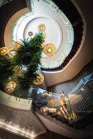 Um interior moderno com escada em espiral, guarda-corpos de vidro e luminárias decorativas.