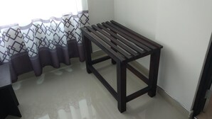 Um quarto com um banco de madeira, cortina estampada e piso ladrilhado.