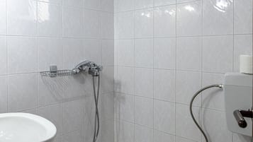 Casa de banho com chuveiro, sanita e lavatório.