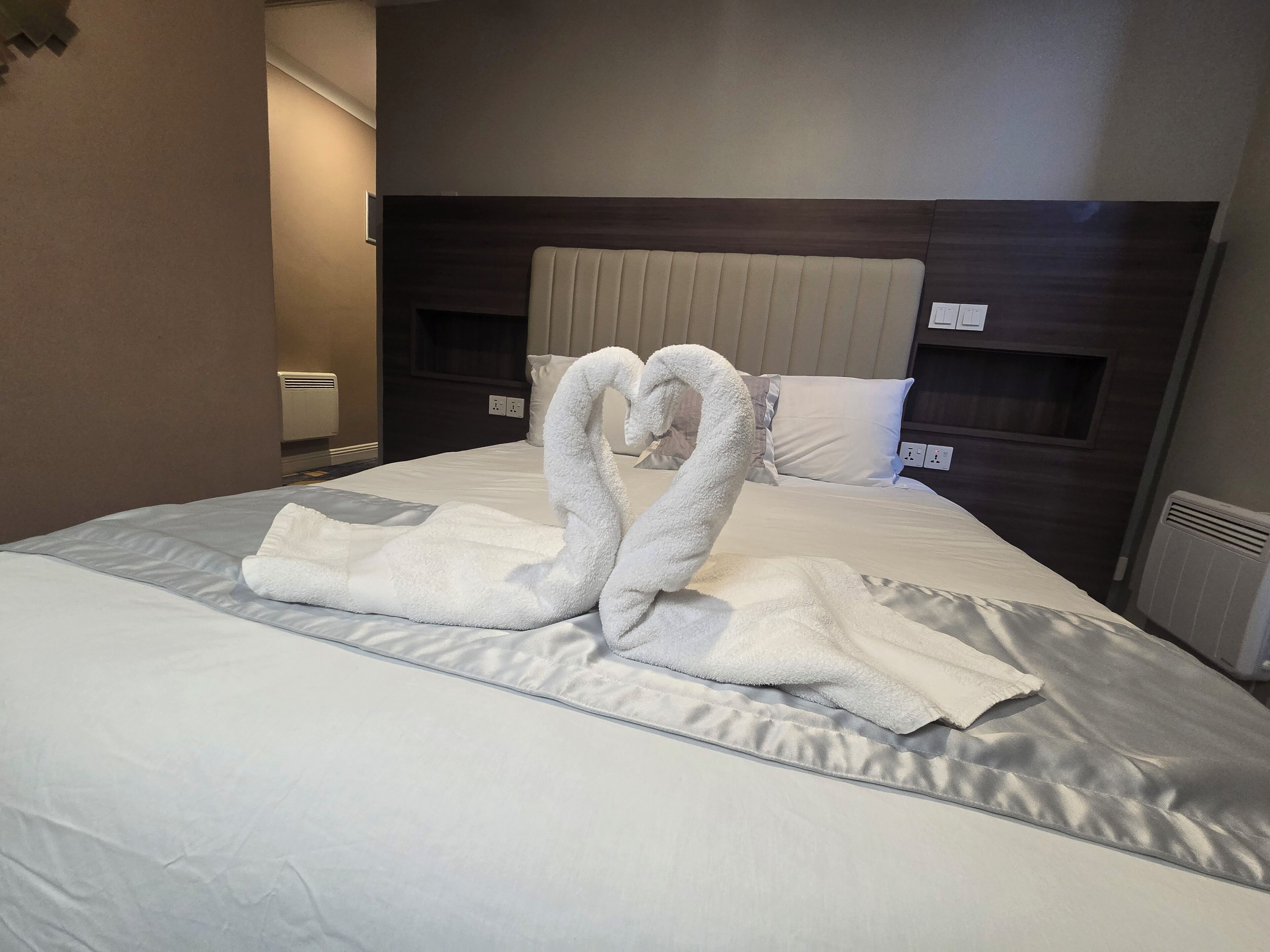 Quarto de hotel com uma cama bem arrumada, cabeceira e unidade de ar condicionado na parede.