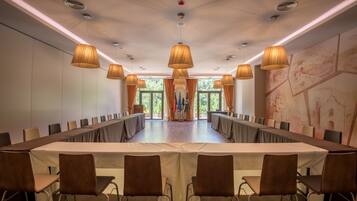 Uma sala de conferência com uma mesa comprida, cadeiras e luminárias pendentes.