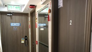 Um corredor com duas portas, uma identificada por uma placa de saída e a outra com um número.